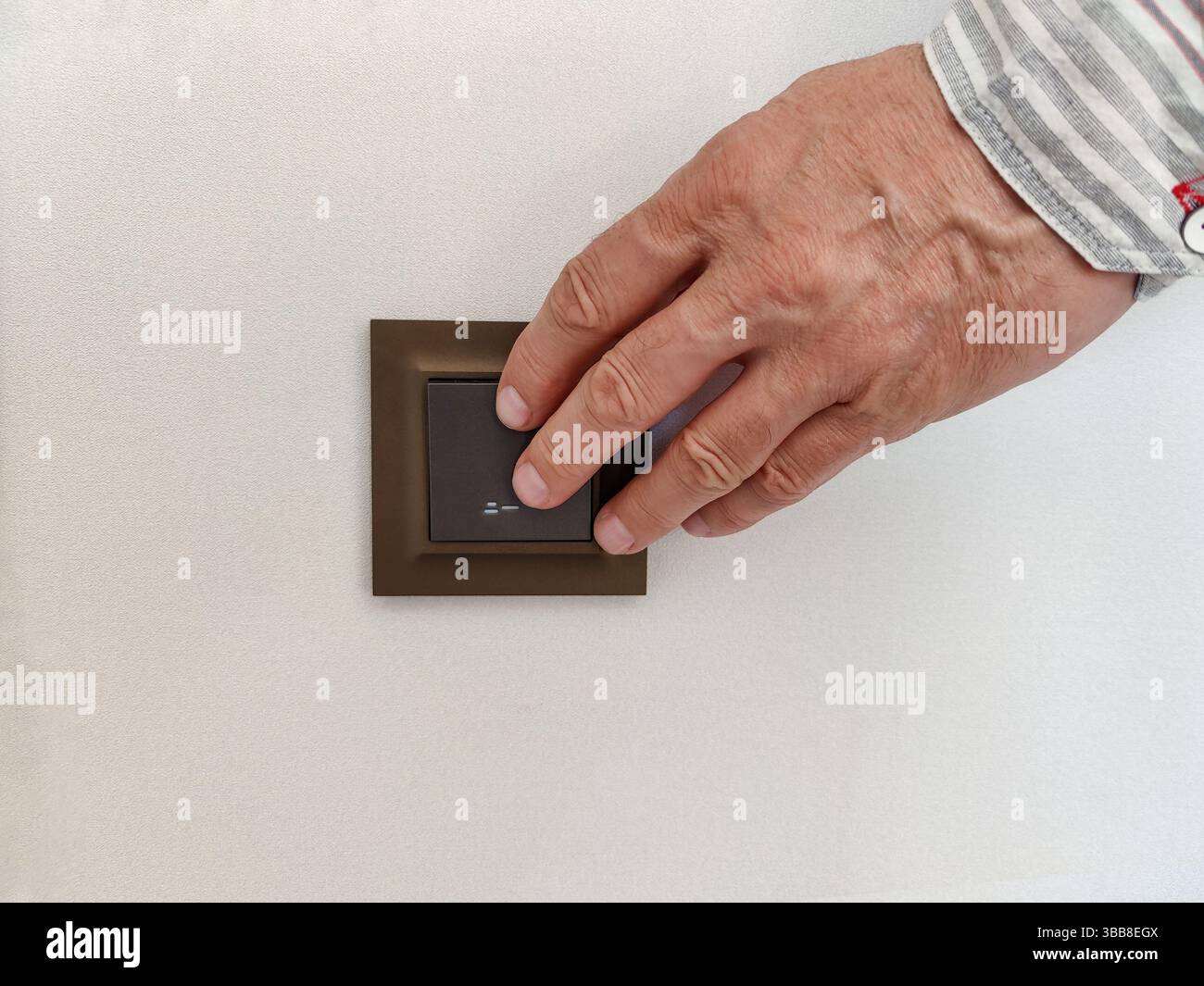Turning light on / off. Man pressing light switch on white wall, close ...
