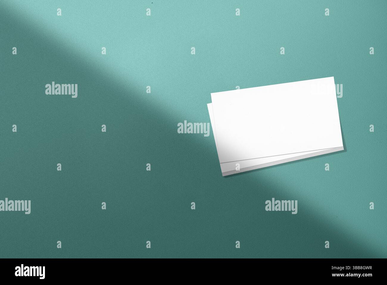 Top view of a stack of business cards with a shadow on a cyan ...