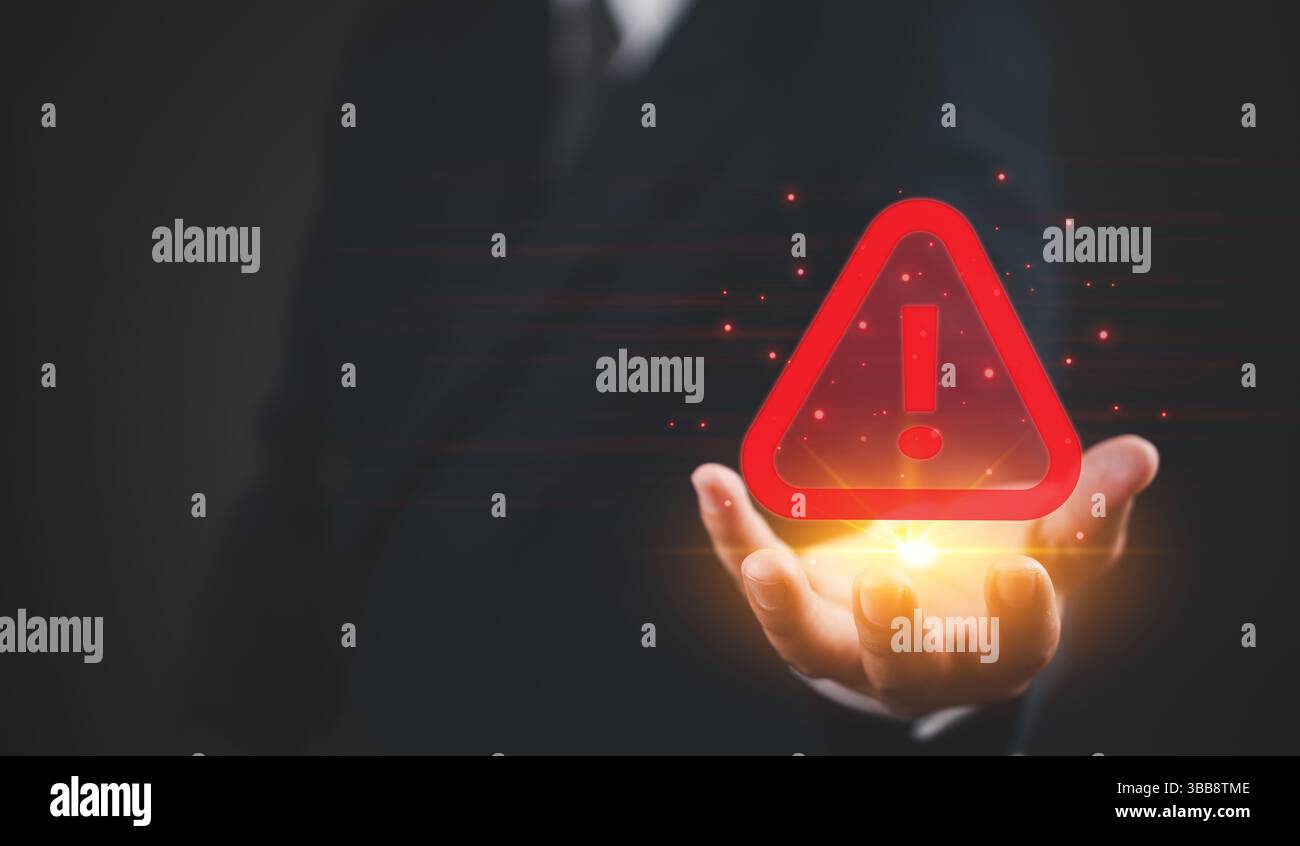 Businessman holding a digital warning triangle, representing ...