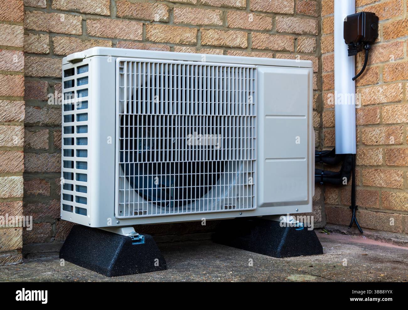 A single heat pump or compressor unit outside a modern house to provide ...