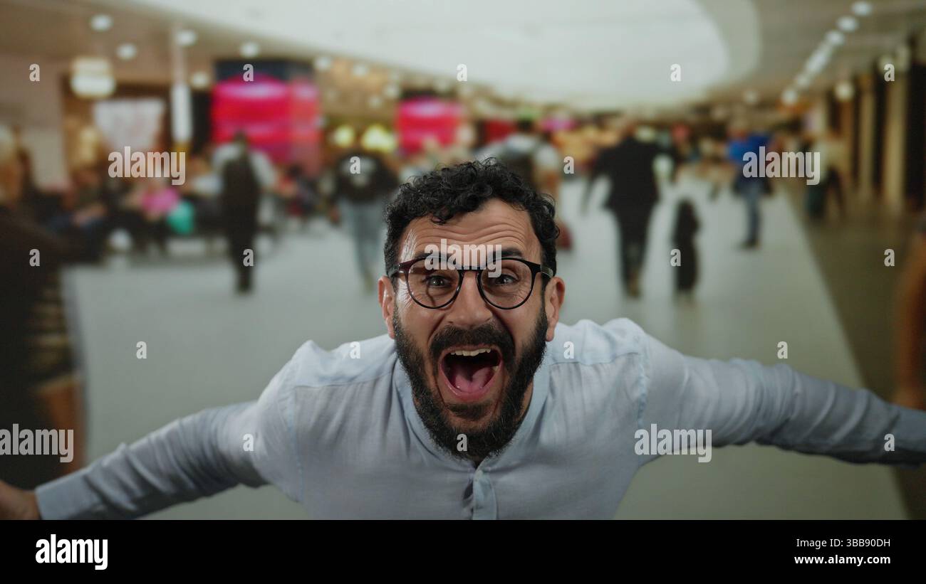 Hispanic man with beard shouting excitedly in bustling shopping center ...
