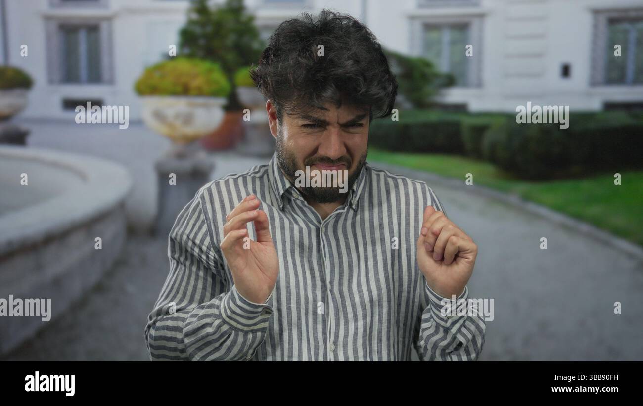 Young man with beard makes a gesture of disgust outdoors on a street ...