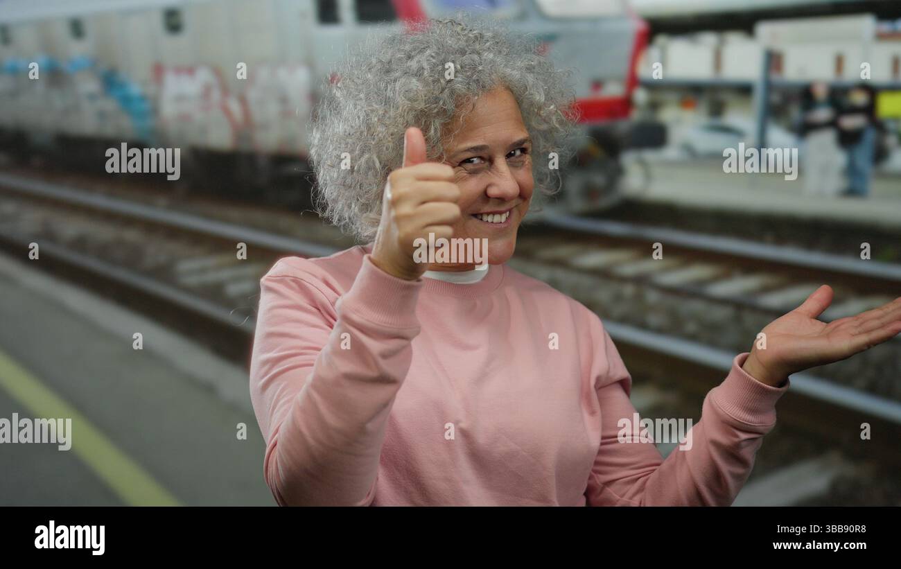 Woman smiling with grey hair gestures at train station, expressing ...