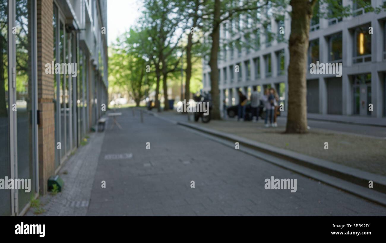Blurry urban street scene shows a group of people casually gathering in ...