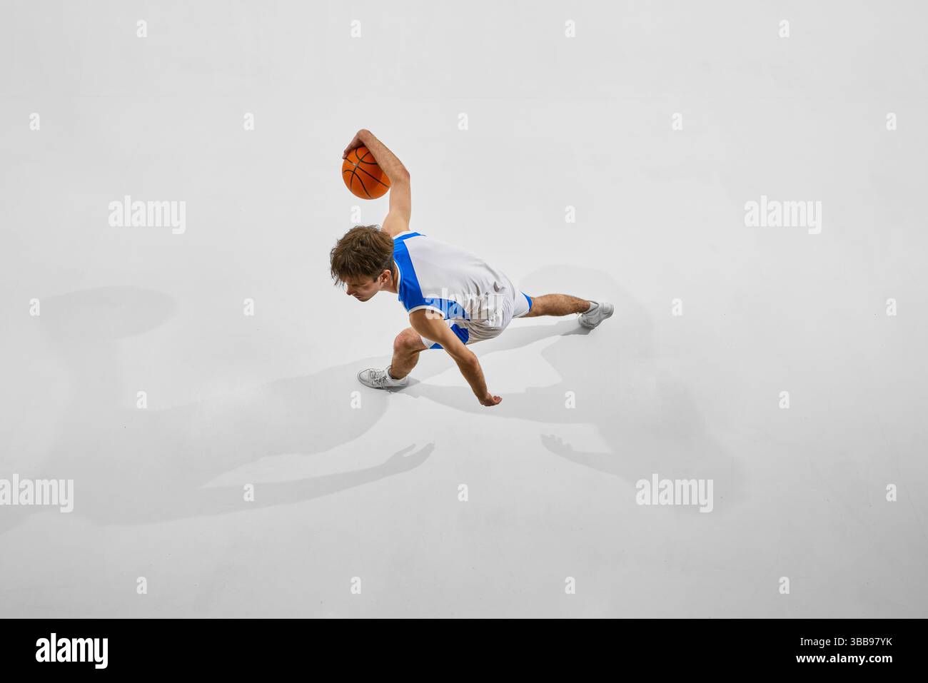 Basketball player training hard, caught from above mid-dribble, showing ...