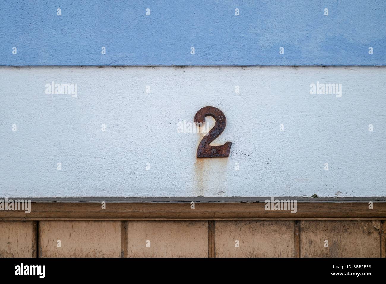 Rusty Number Two on Textured Wall. Close-up of a weathered, rusty metal ...