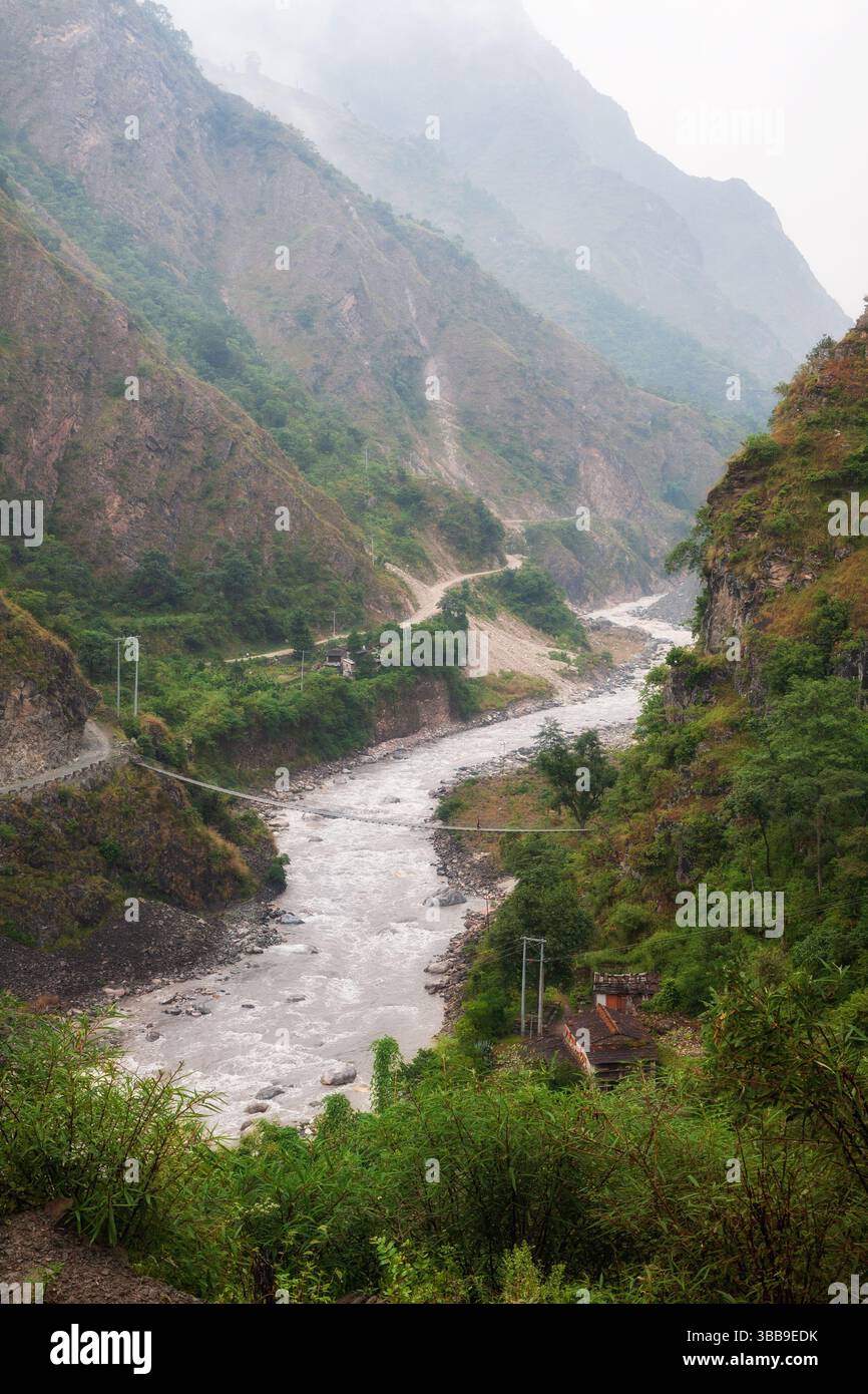 Kali Gandaki River Gorge in the morning mist. Suspension bridge over ...