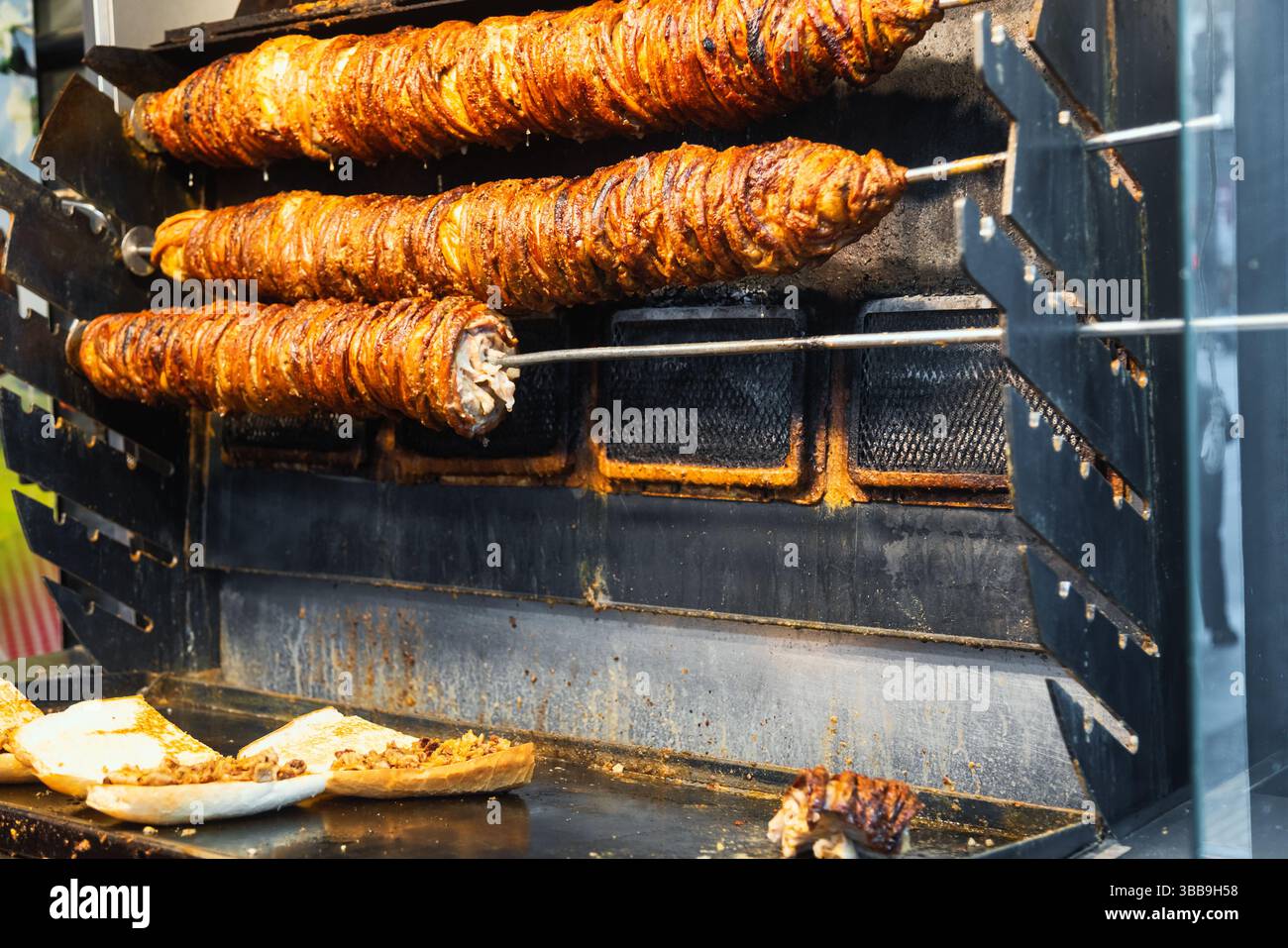 Seasoned kokorec skewers made of lamb intestines roast on a rotisserie ...