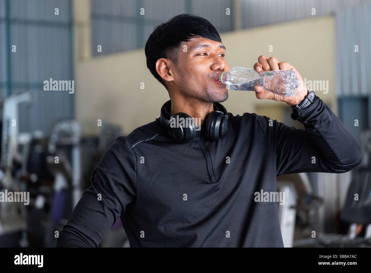 Hydration and Fitness. Man drinking water after exercise in a gym ...