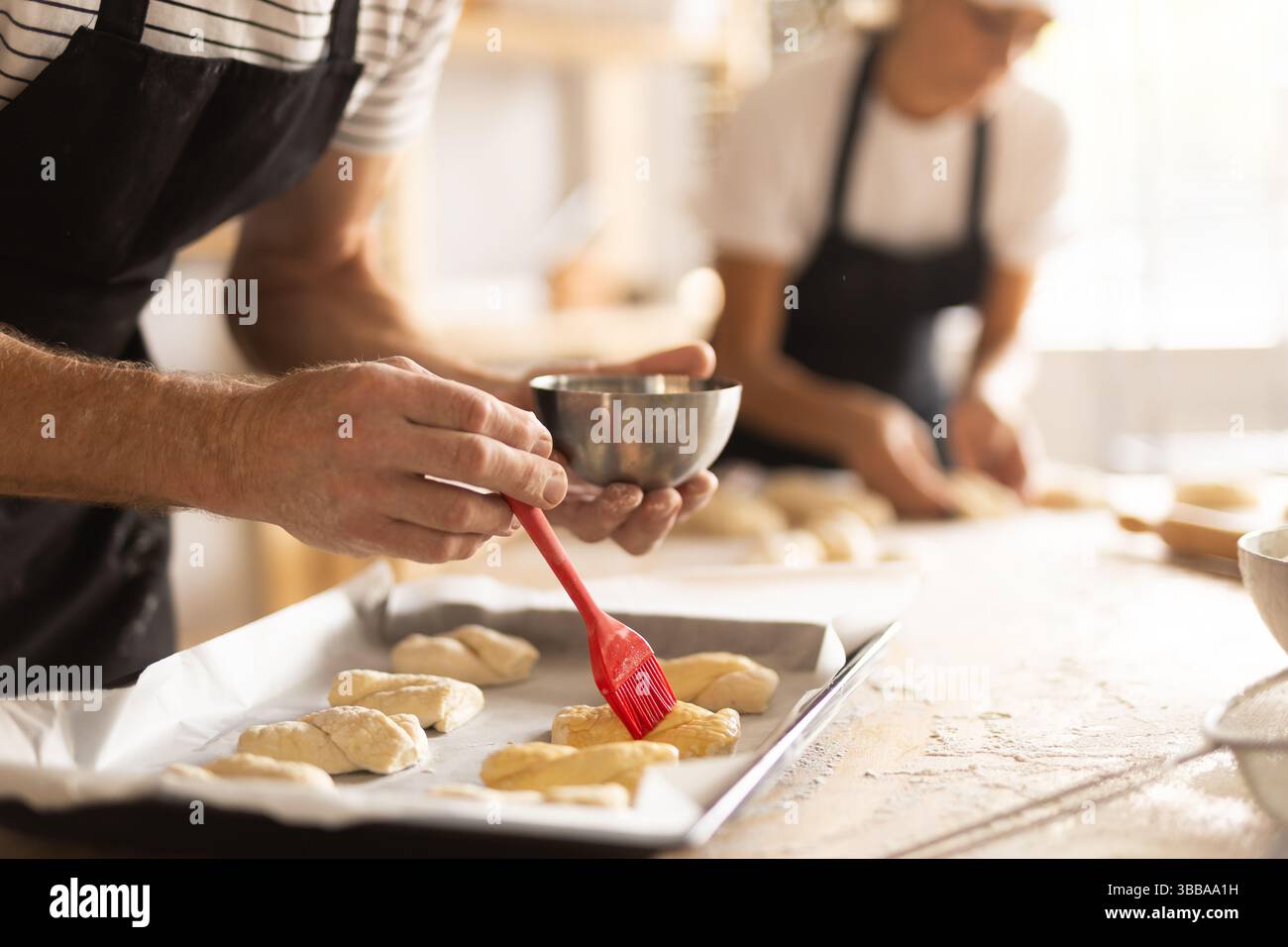 Baker's hands grease pieces of dough on baking sheet Stock Photo - Alamy