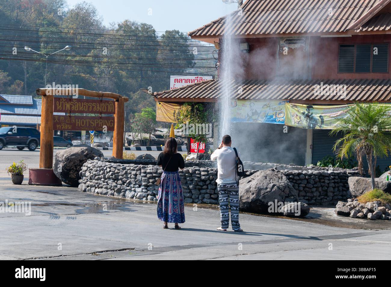 A couple of tourists at the spouting hot spring near the main entrance ...