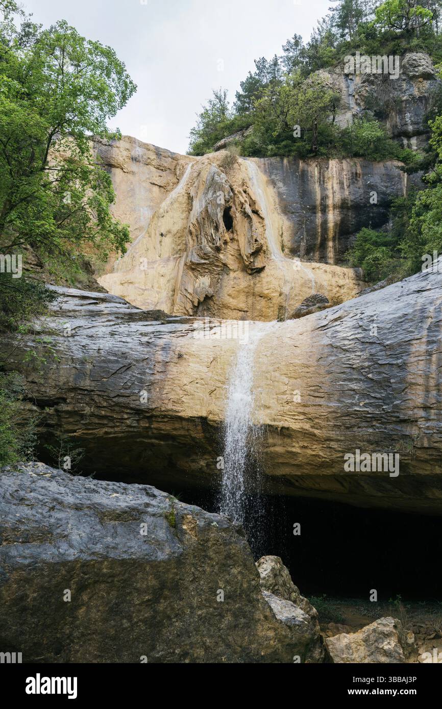 Secluded waterfall cascading into turquoise grotto pool. Limestone cave ...