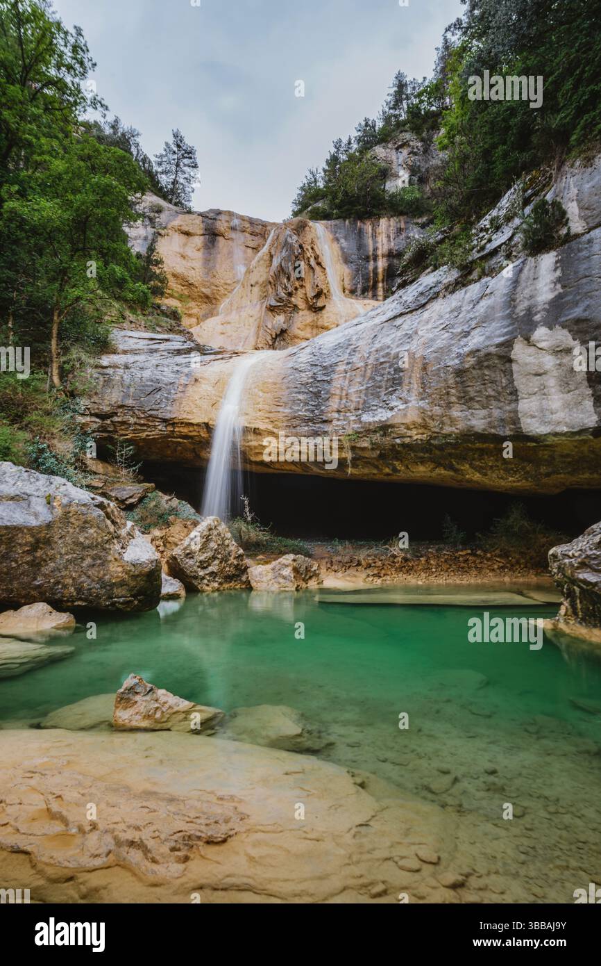 Waterfall cascading into turquoise pool in limestone cavern. Secret ...