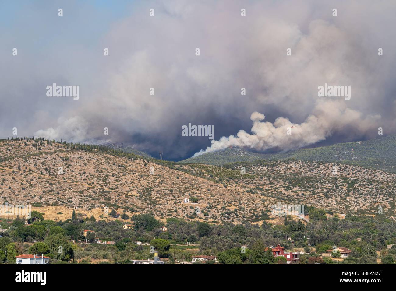 Heavy smoke from an intense forest wildfire rises over dry hills ...