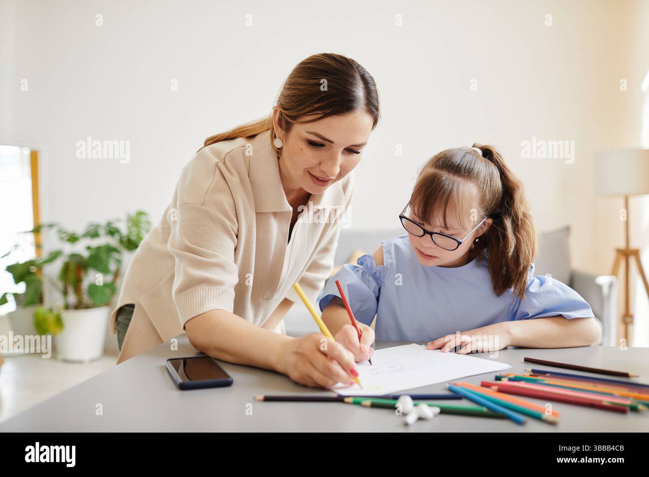Girl with Down Syndrome doing Homework with Mom Stock Photo - Alamy