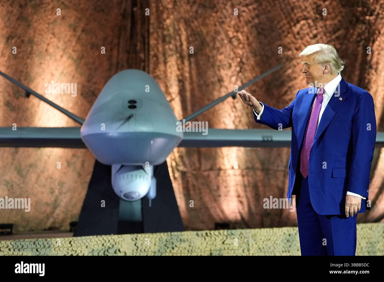 President Donald Trump stands backdropped by an MQ-9 Reaper drone ...