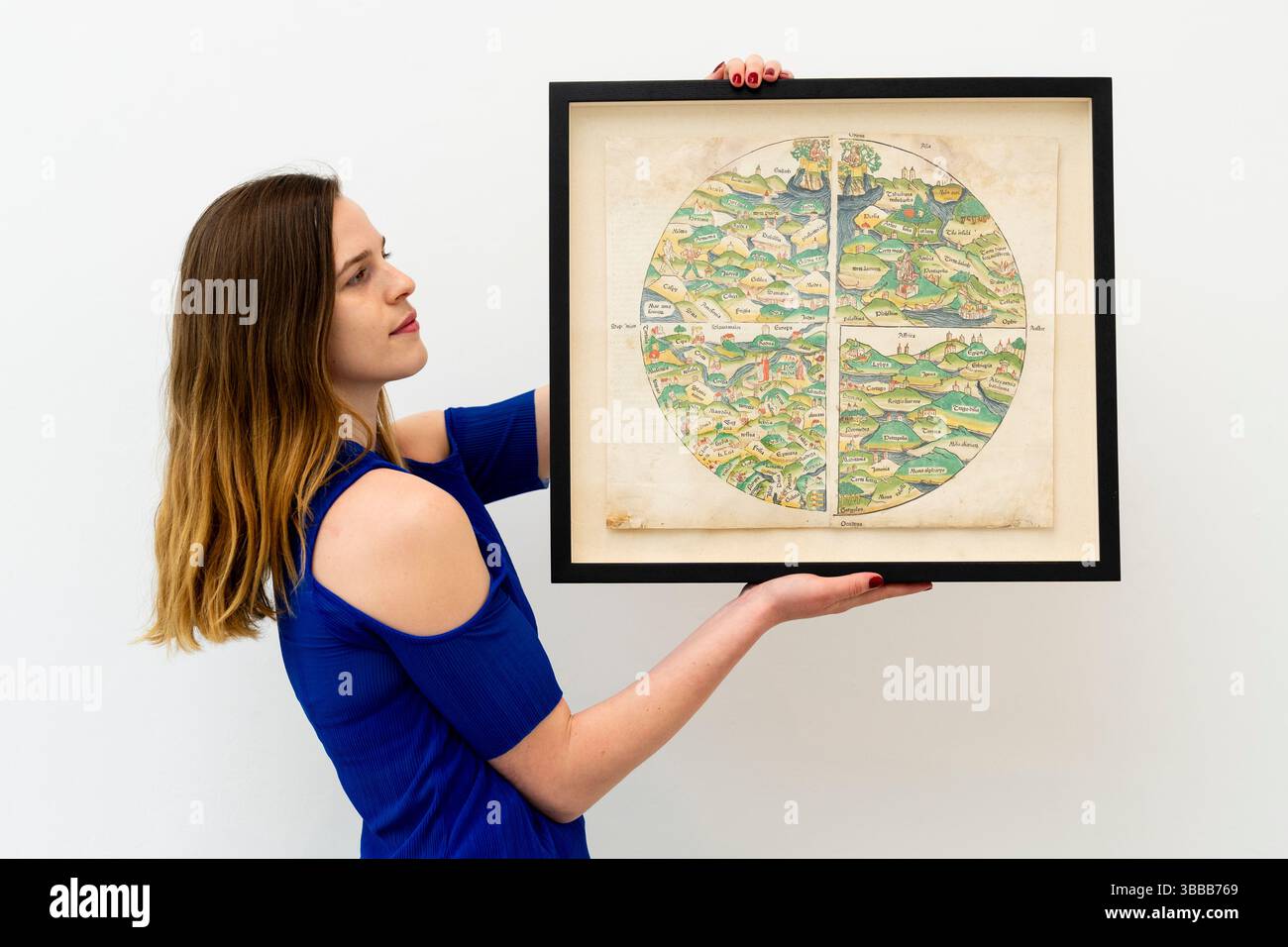 An exhibitor holds up the earliest printed map of the world from 1475 ...