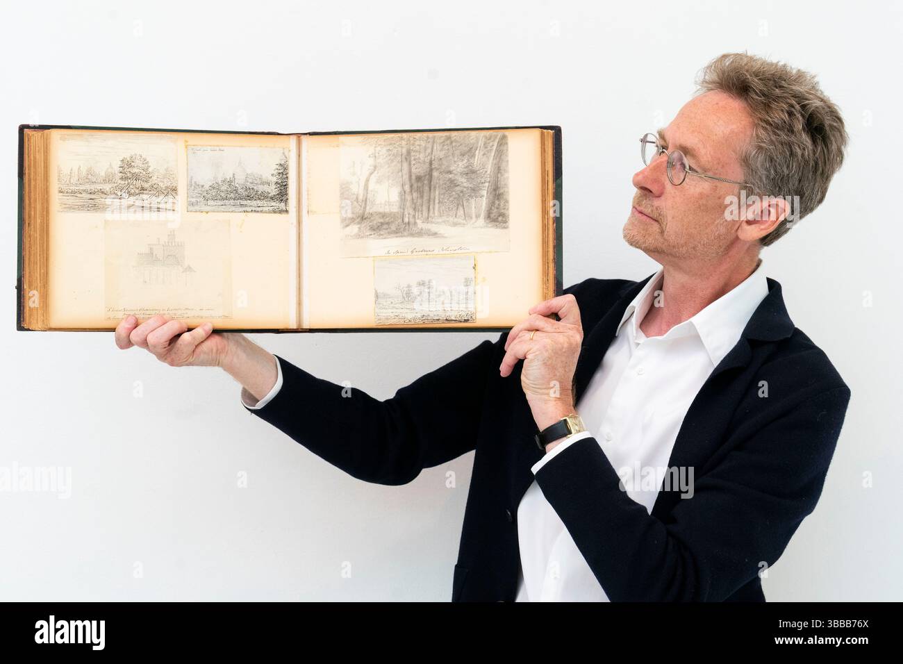Justin Croft holds up an album of drawings which shows a view of St ...