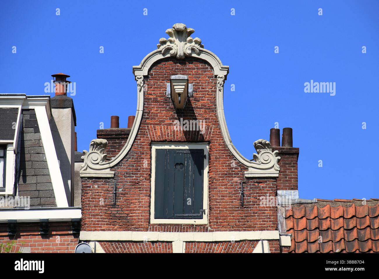 Historic brick house facade with decorated bell (or clock) gable close ...
