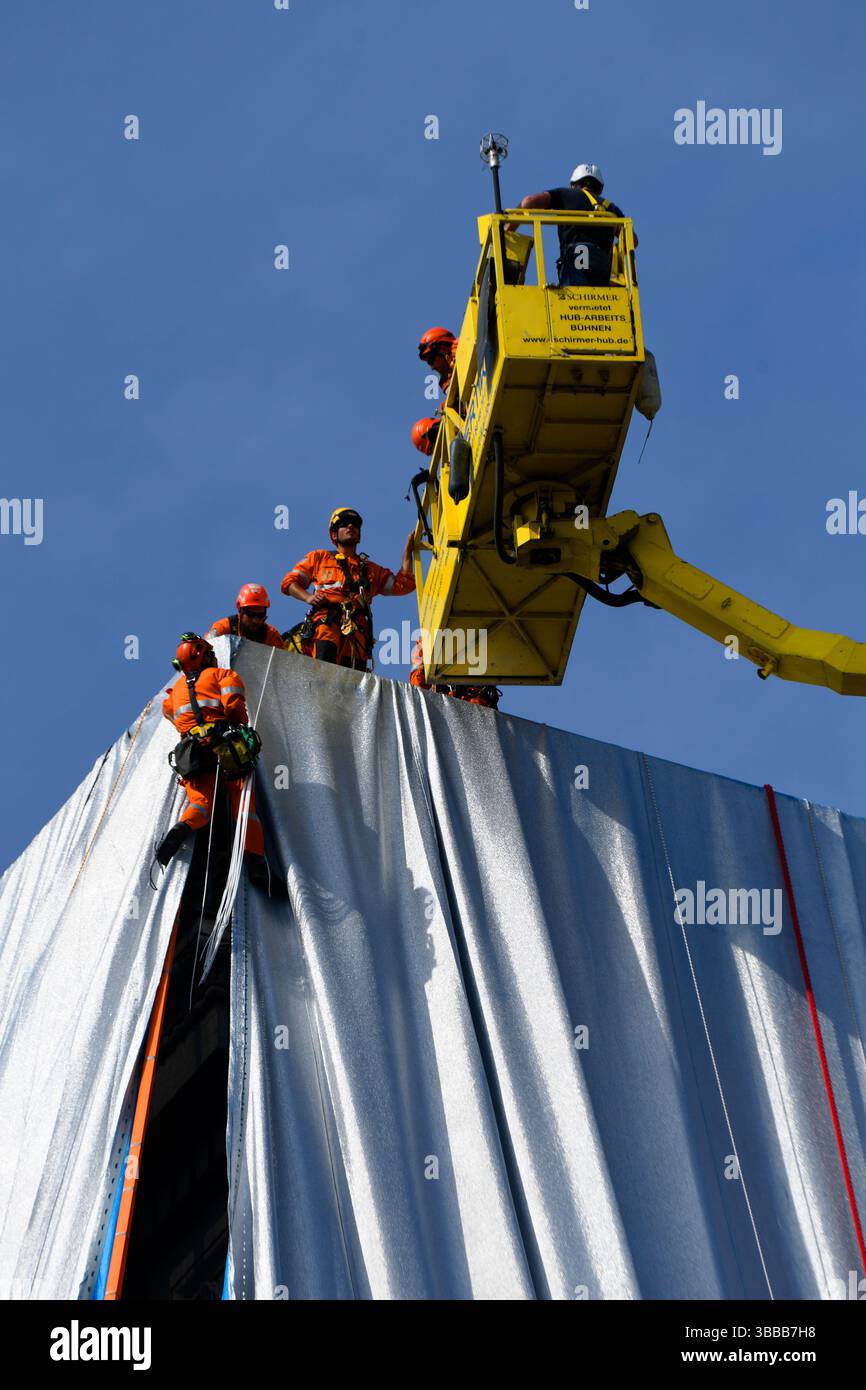 Workers install a shimmering wrapper to envelop Paris landmark, the Arc ...