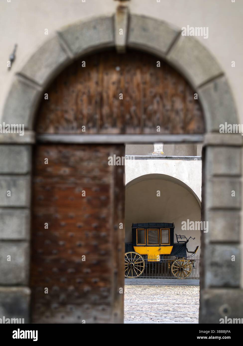 A vintage horse-drawn carriage in a courtyard, framed by an arched ...