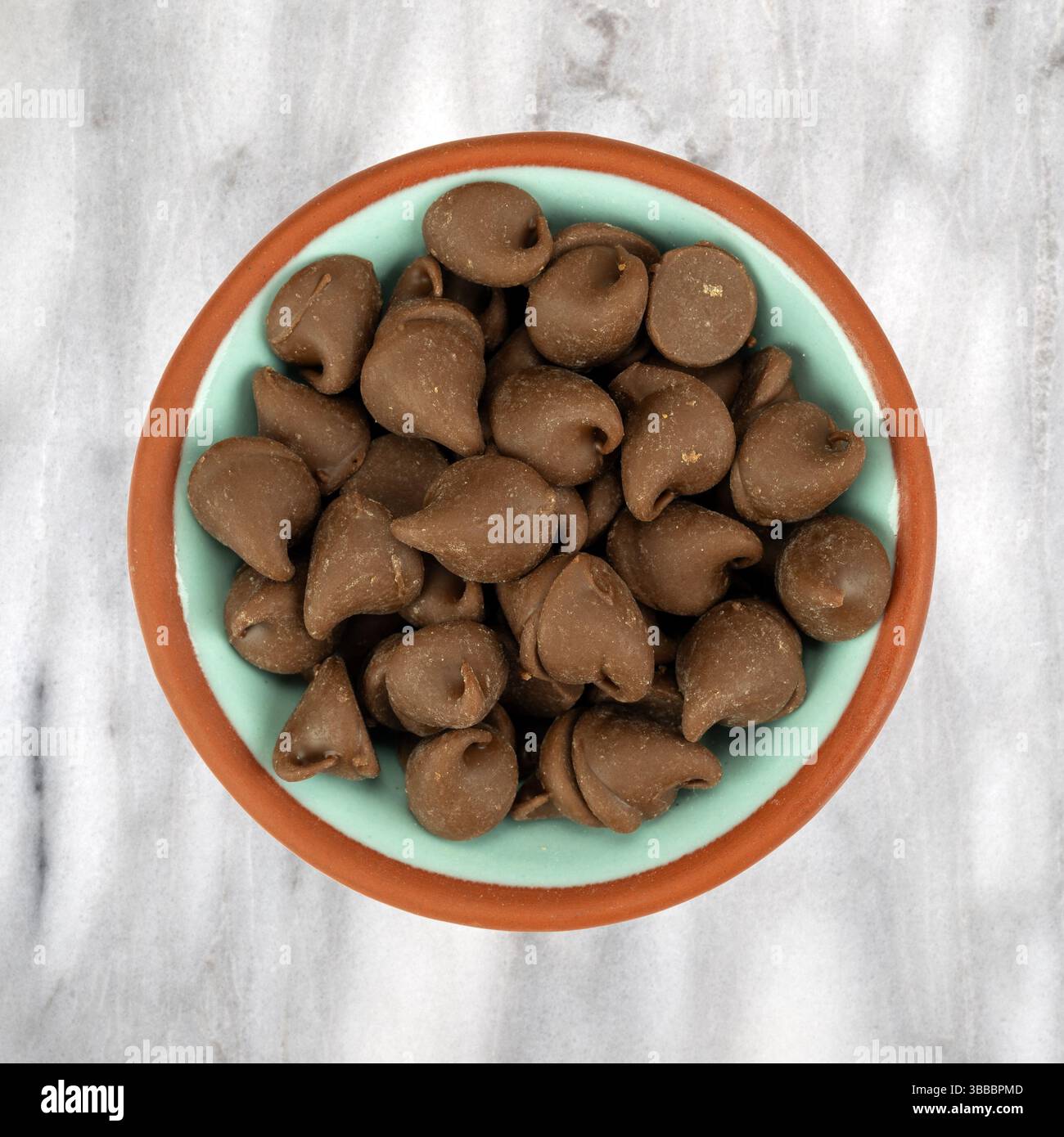 Top view of a small bowl filled with milk chocolate chips on a gray ...