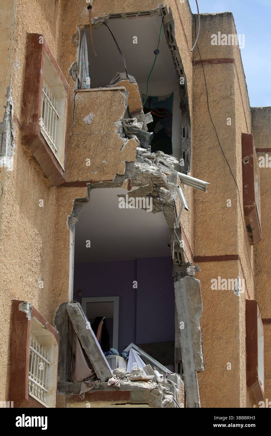 Palestinians inspect the damage around a destroyed building after ...
