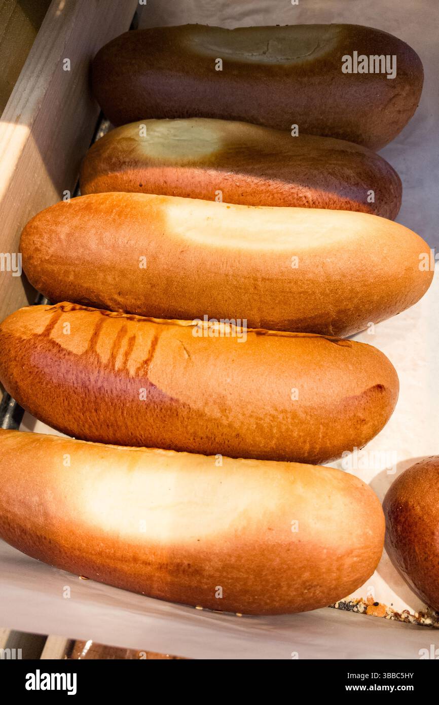 Warm and golden-brown bread rolls rest in a wooden basket, exuding an ...