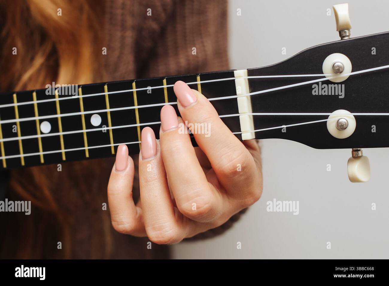 Woman playing ukulele chords. Female fingers on strings. Learning ...