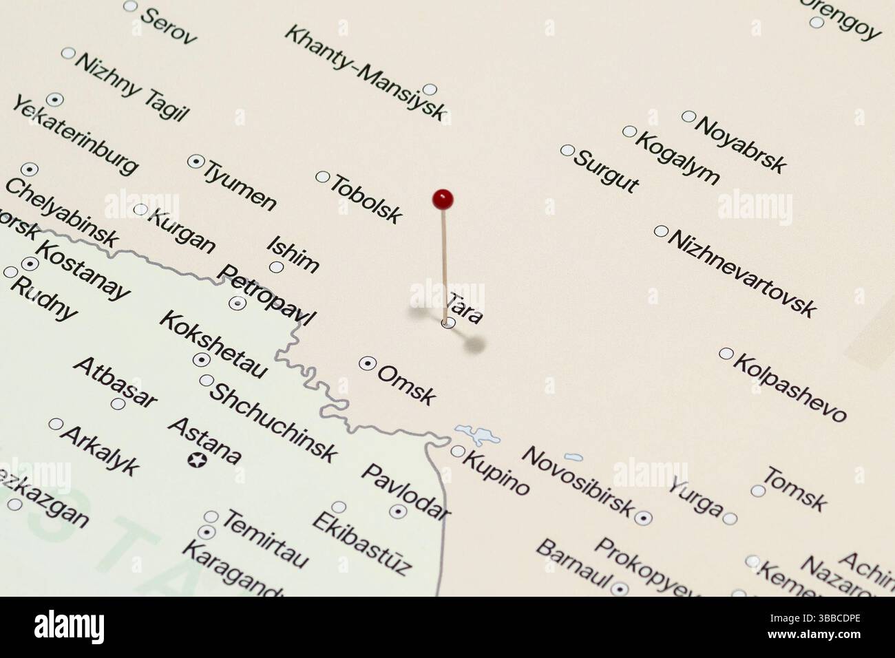 macro photo of a red pin needle into tara city of Russia political map ...
