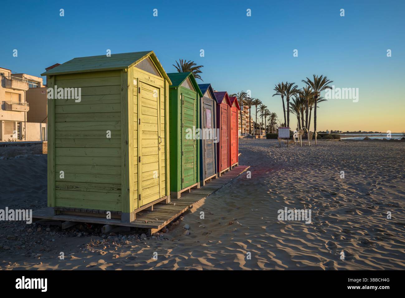 Row of colorful wooden beach changing huts in yellow, green, blue ...