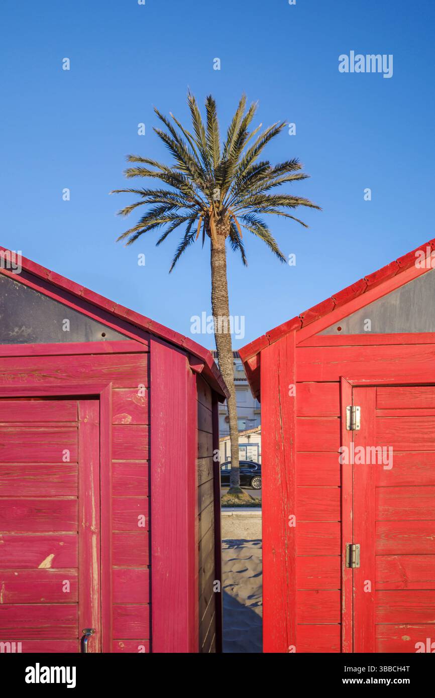 Tall palm tree perfectly centered between bright red wooden beach ...