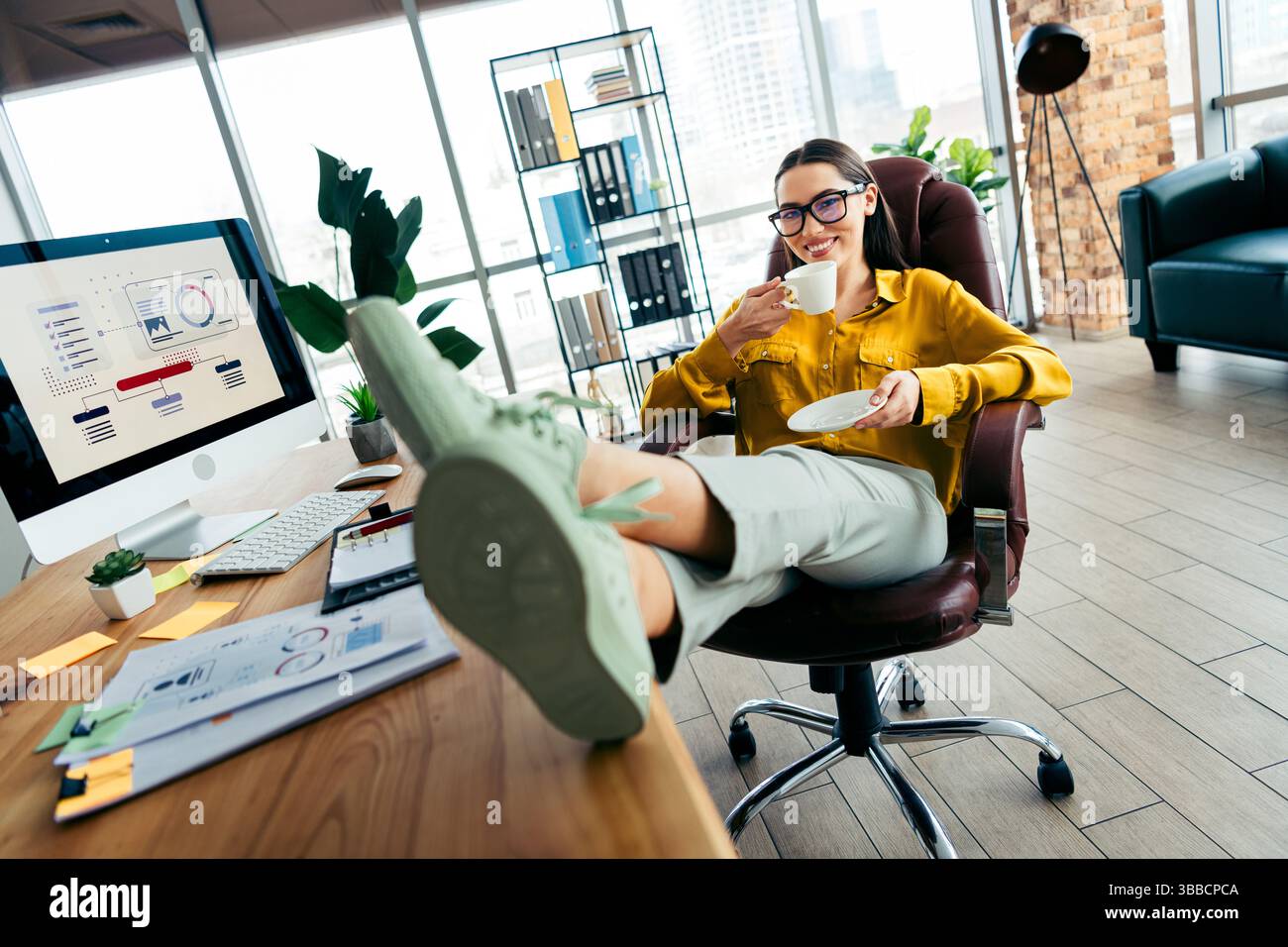 Young professional woman enjoying a coffee break in modern workplace ...