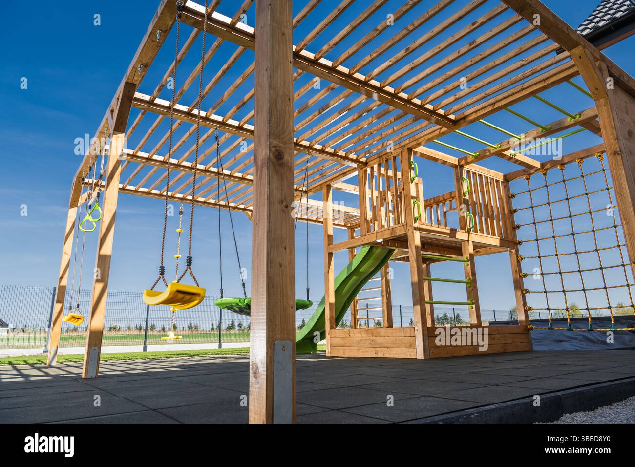 A well-designed wooden playground features swings, a slide, and a ...