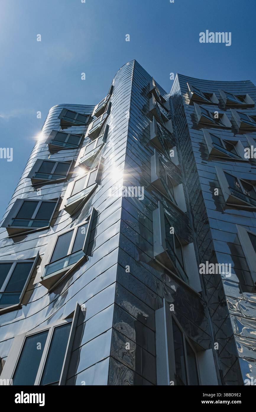 Shiny modern building designed by Frank Gehry with curved metal facade ...