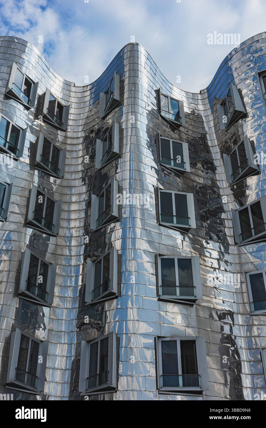 Shiny modern building designed by Frank Gehry with curved metal facade ...