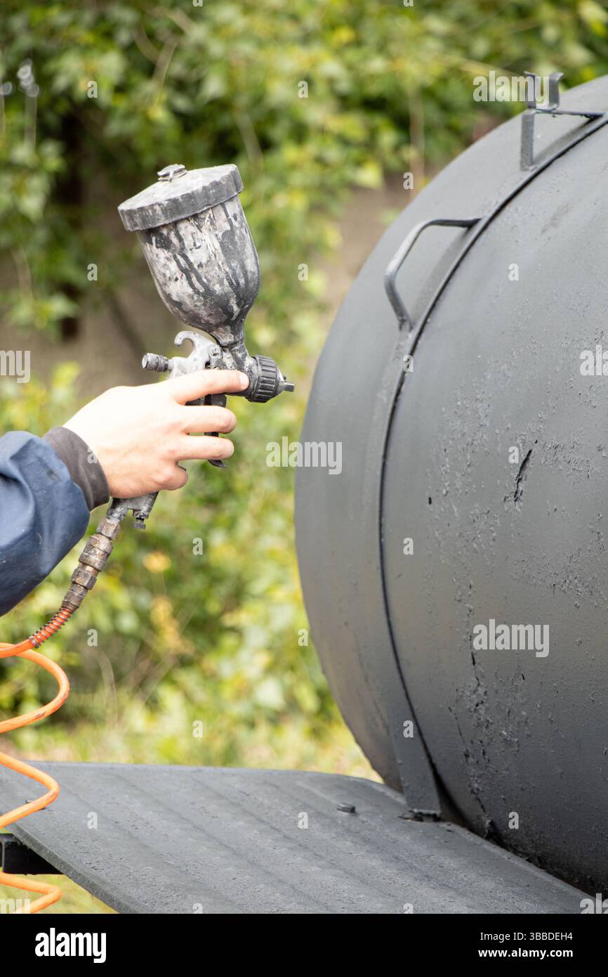 Painting a metal barrel with a spray gun outdoors in Ukraine Stock ...