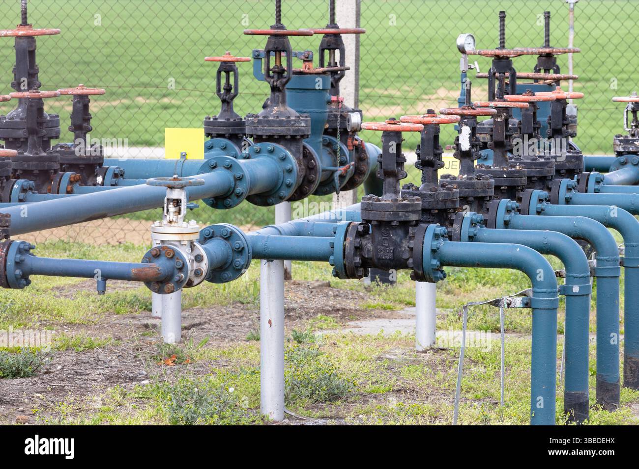 Gas extraction machinery with valves stands in a lush green field with ...
