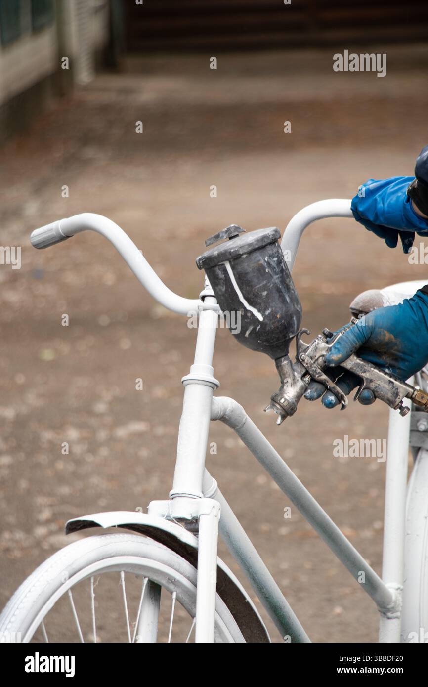 Painting an old bicycle with an airbrush outdoors in white, bicycle ...