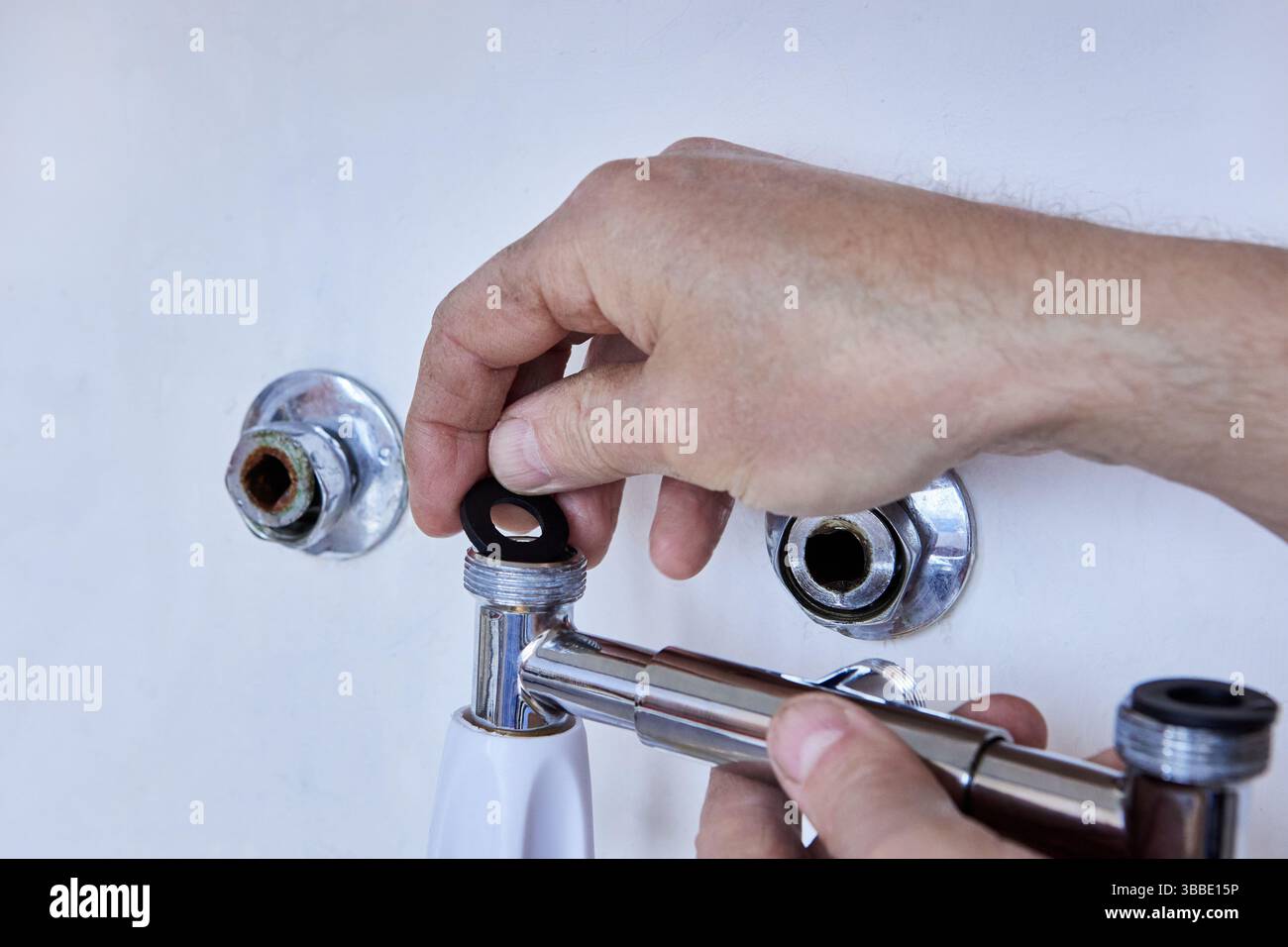 Hands prepare installation of wall mounted dual handle faucet by ...