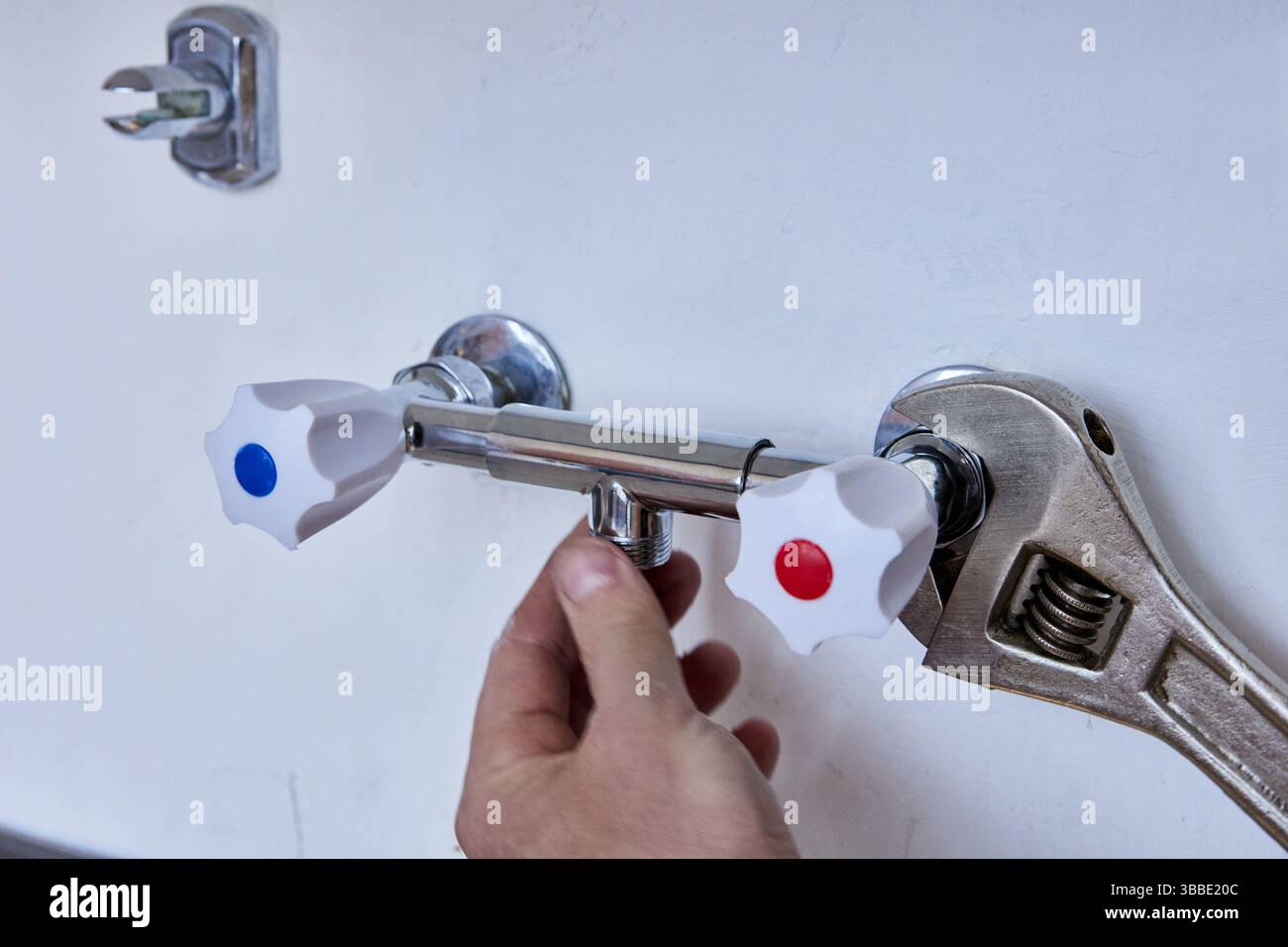 Hand holds body of dual handle faucet while adjustable wrench fastens ...