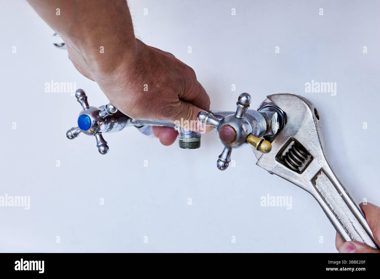 Loosening old dual handle tap fixture with blue and red indicators ...