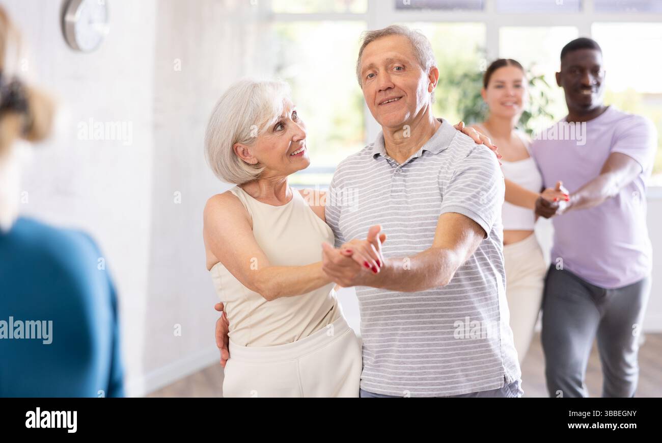 Mature male novice student of fitness studio practices paired Latin ...