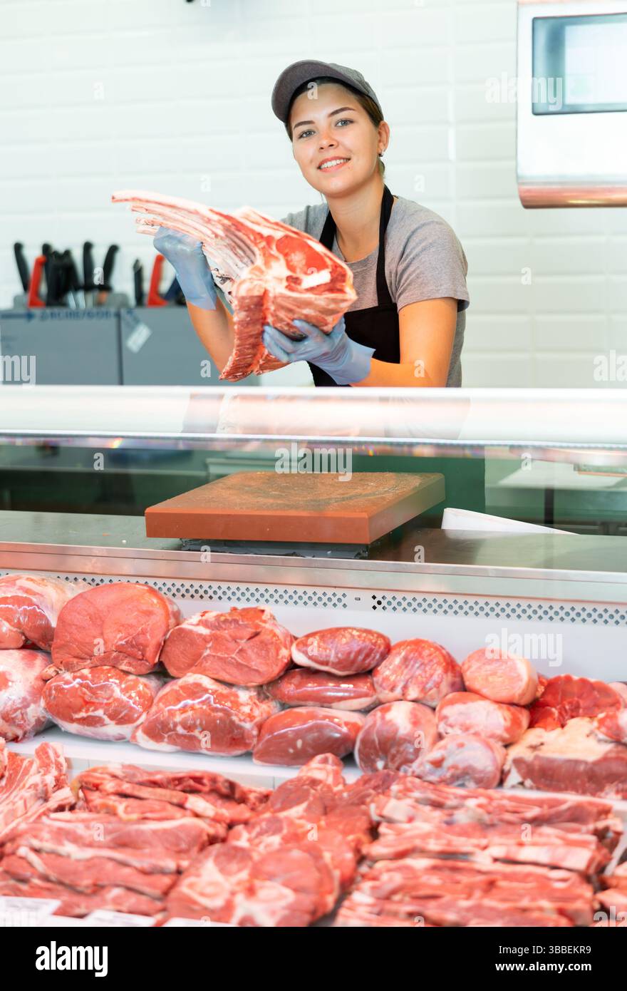 Young woman seller laying out beef ribs in butcher shop Stock Photo - Alamy
