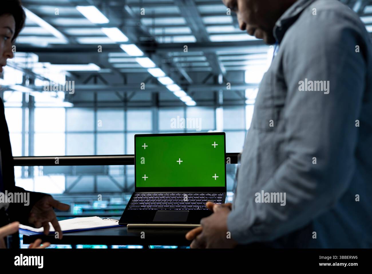 Teamworking coworkers in data center using automation tools on green screen mockup laptop ...