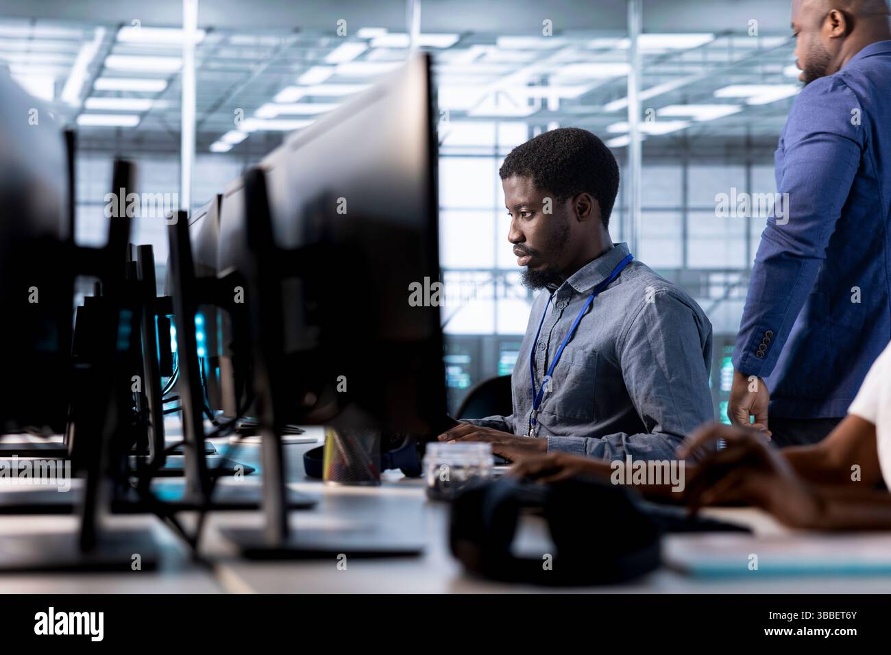 Engineer next to coworkers in server farm checking recovery plan, monitoring data center energy ...
