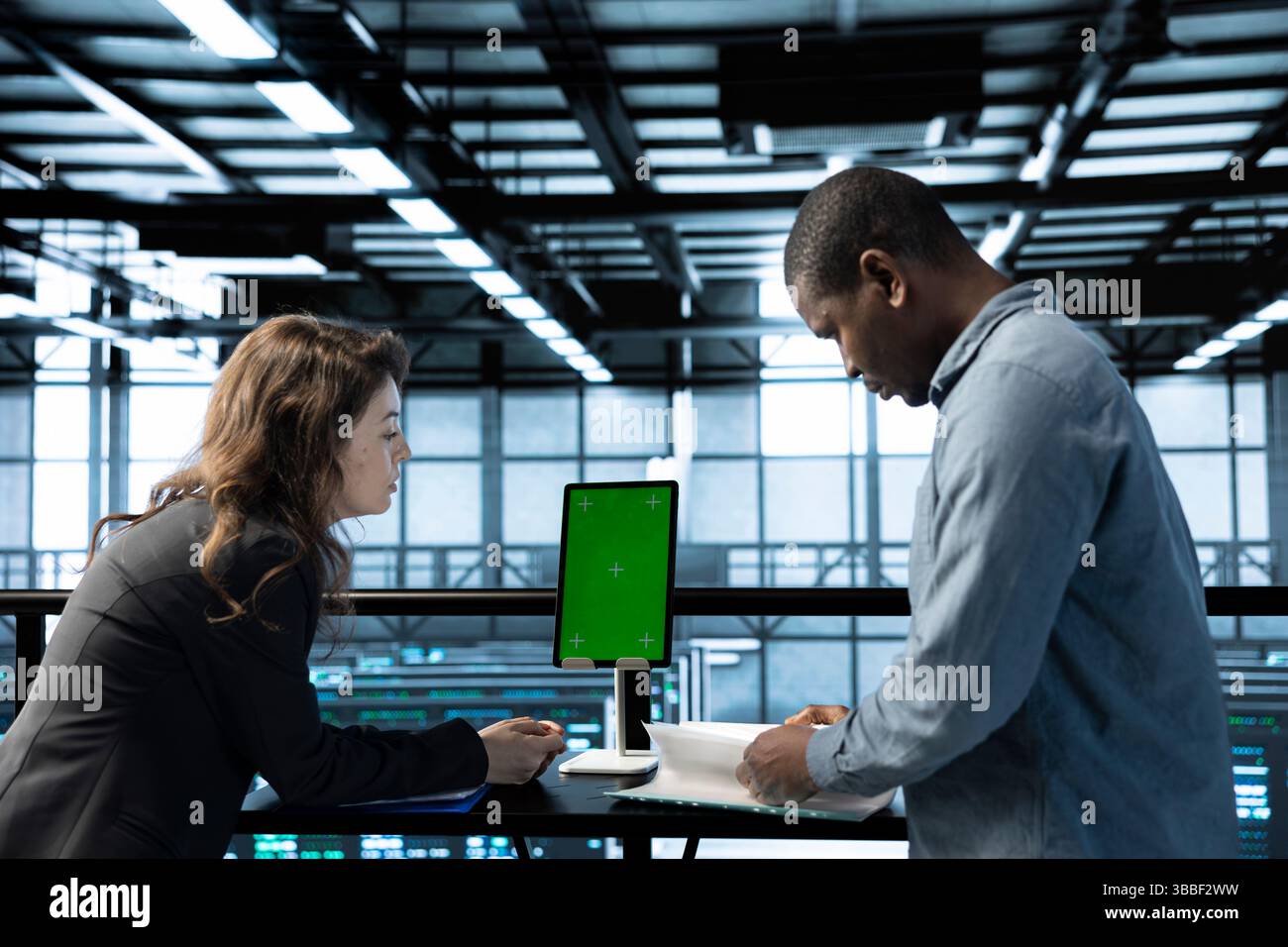Woman overseeing server room with mockup device, reading documentation ...