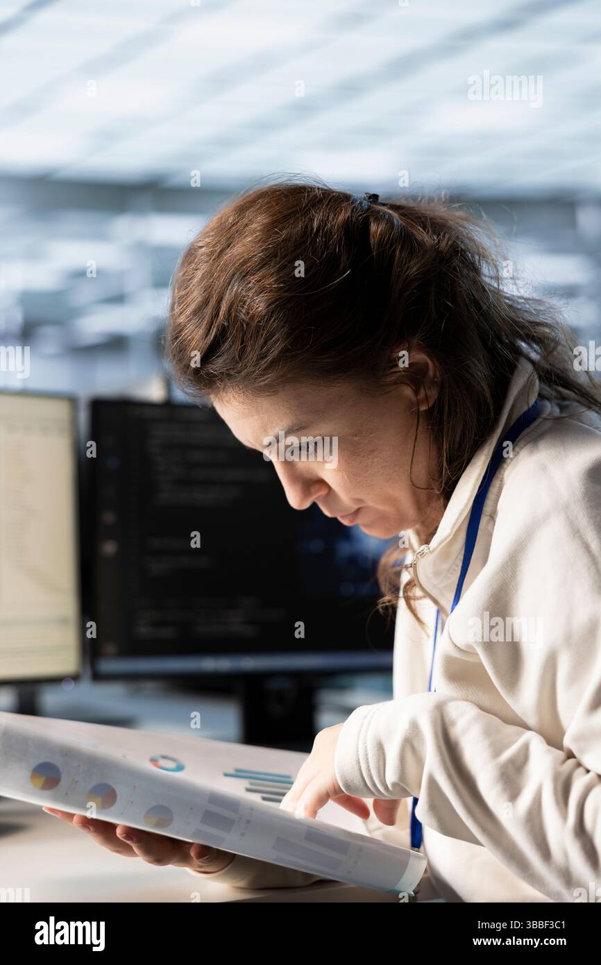 Management executive looking over paperwork in server farm to ensure ...