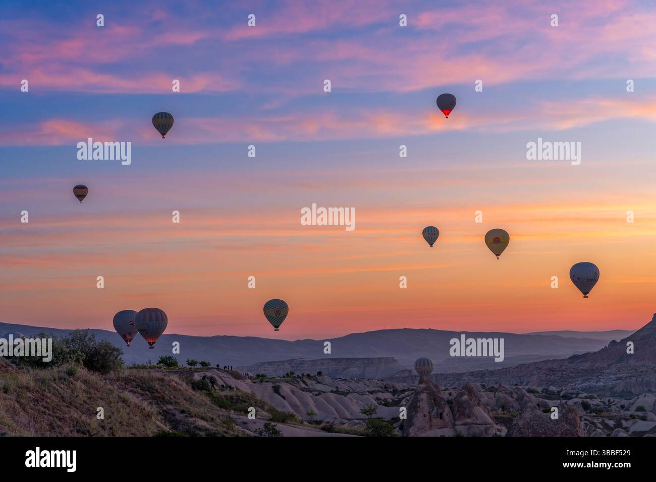Multiple hot air balloons drift over the pastel-colored sky above Love ...