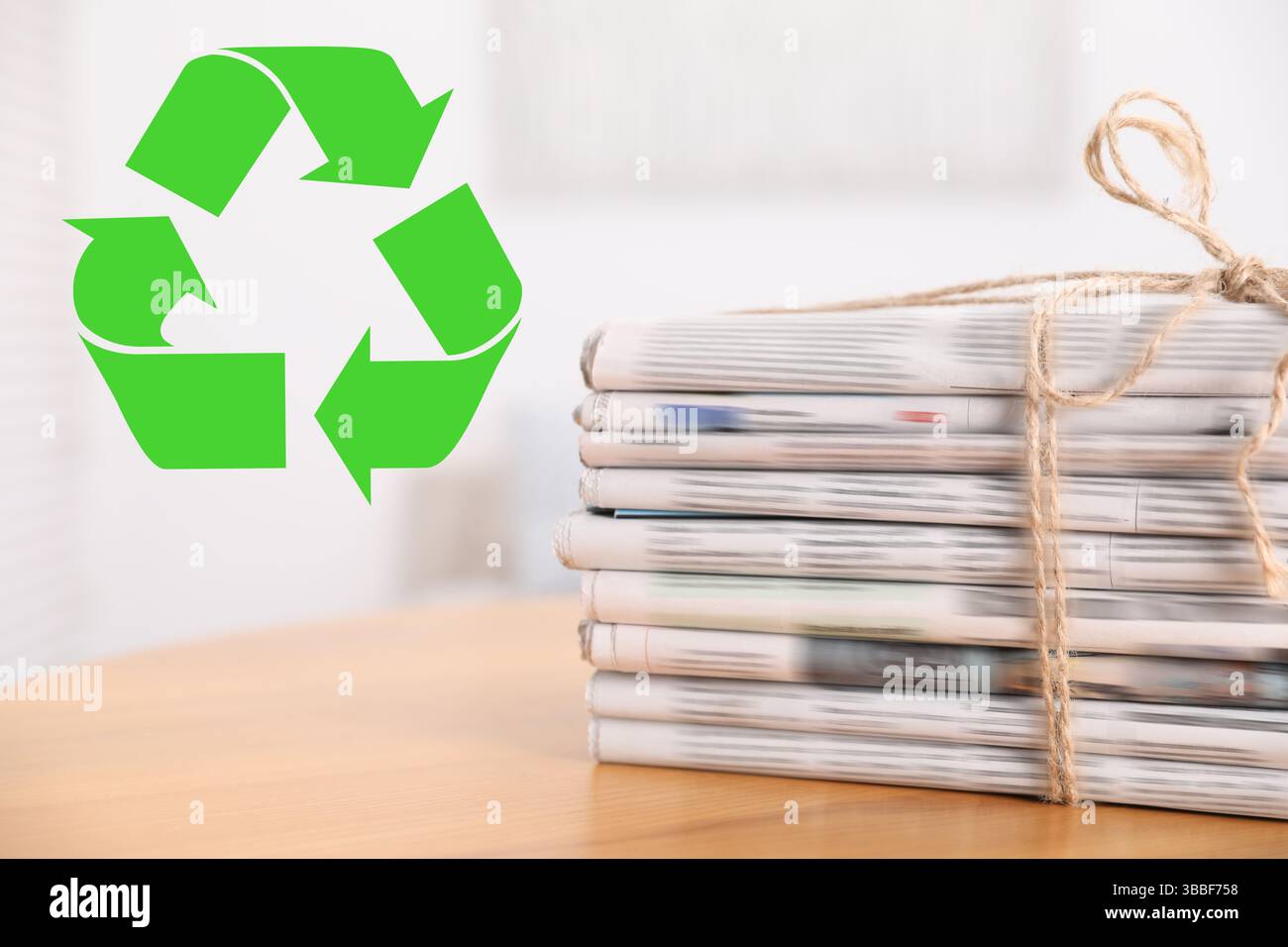 Recycling symbol and stack of tied newspapers on wooden table, closeup ...